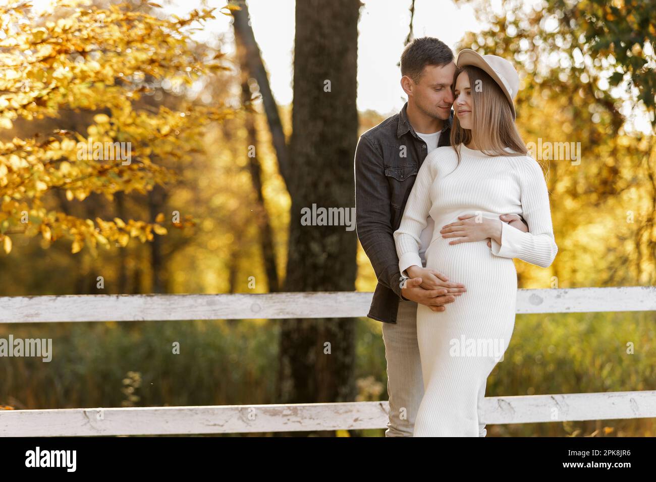 Happy stylish pregnant woman and man hugs, kiss, touches belly and ...