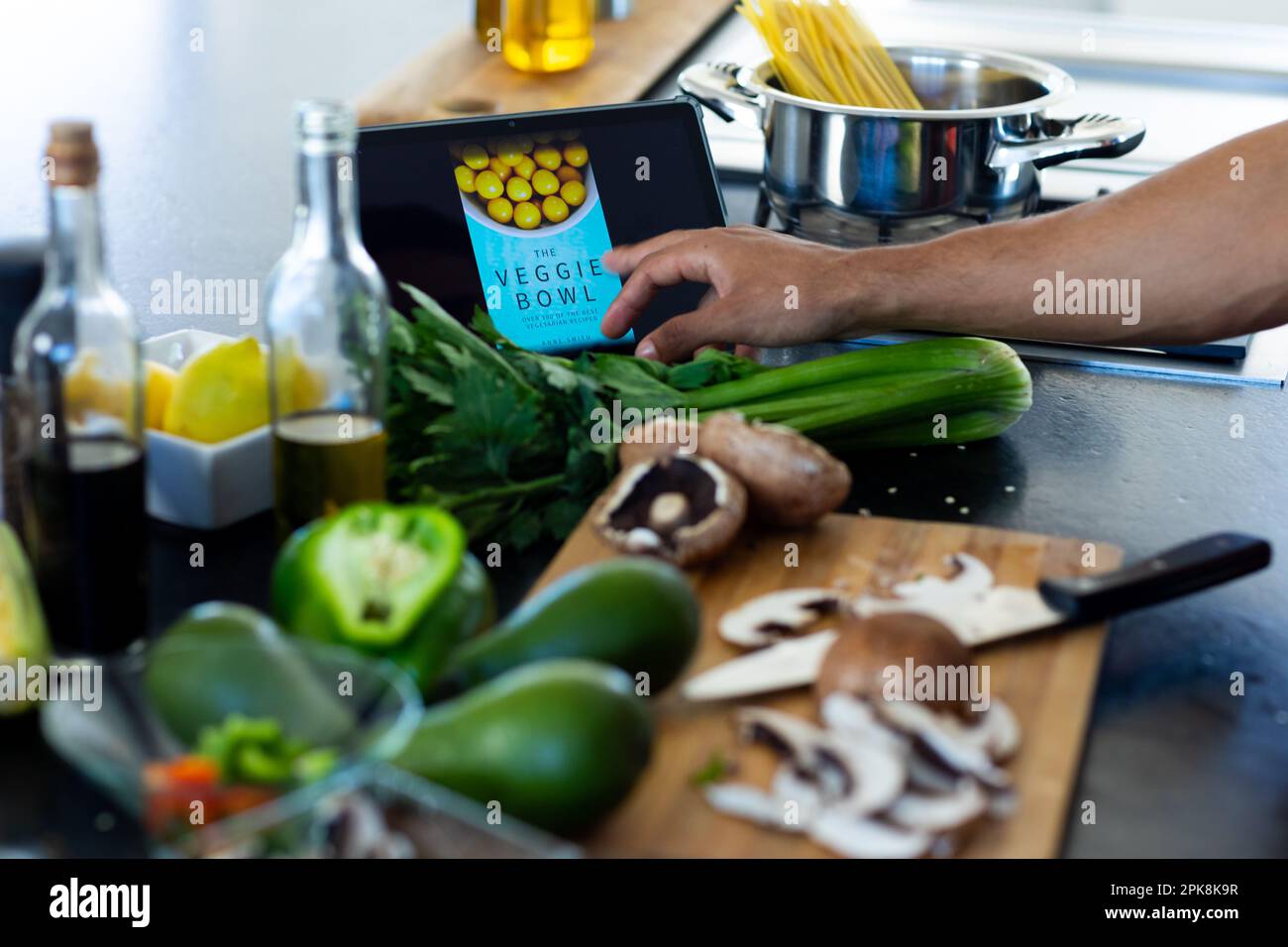 Close up of hands of biracial man preparing dinner, using tablet in ...
