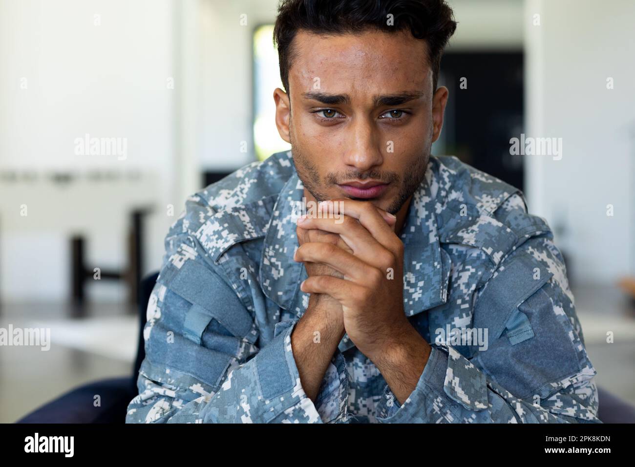 Worried biracial male soldier wearing military uniform, sitting in ...