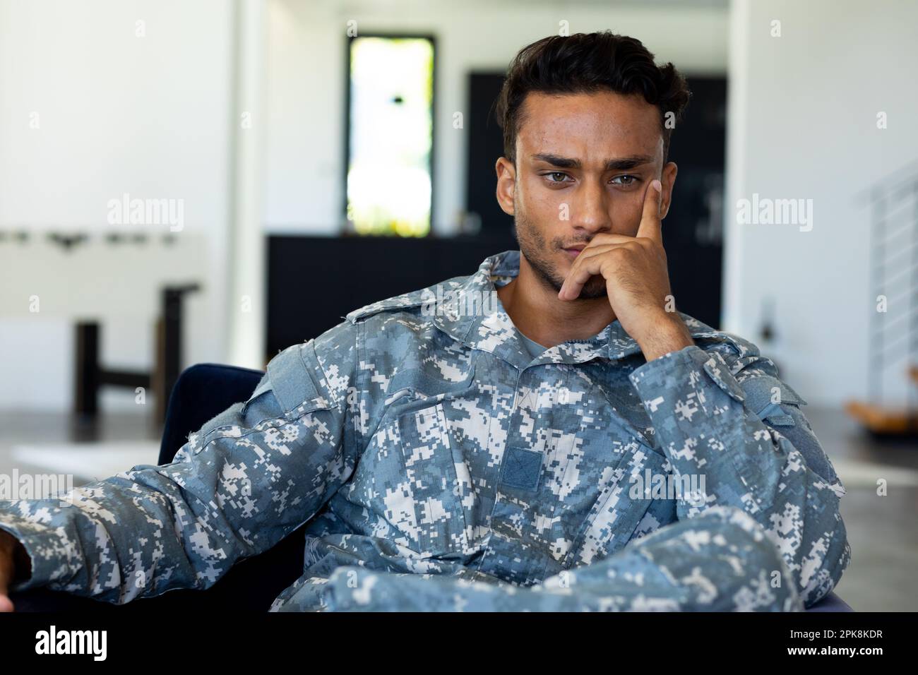 Worried biracial male soldier wearing military uniform, sitting in ...