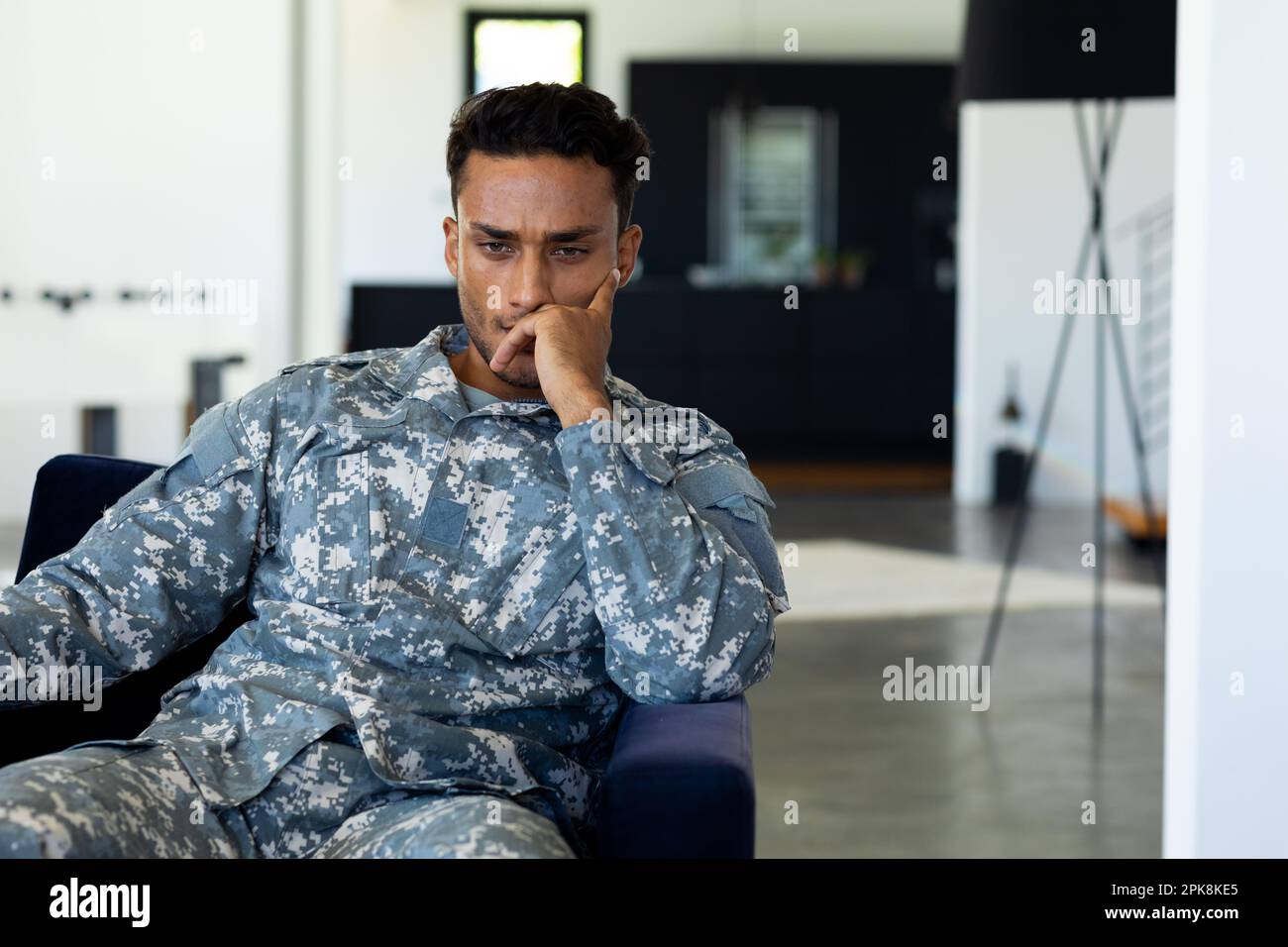Worried biracial male soldier wearing military uniform, sitting in ...