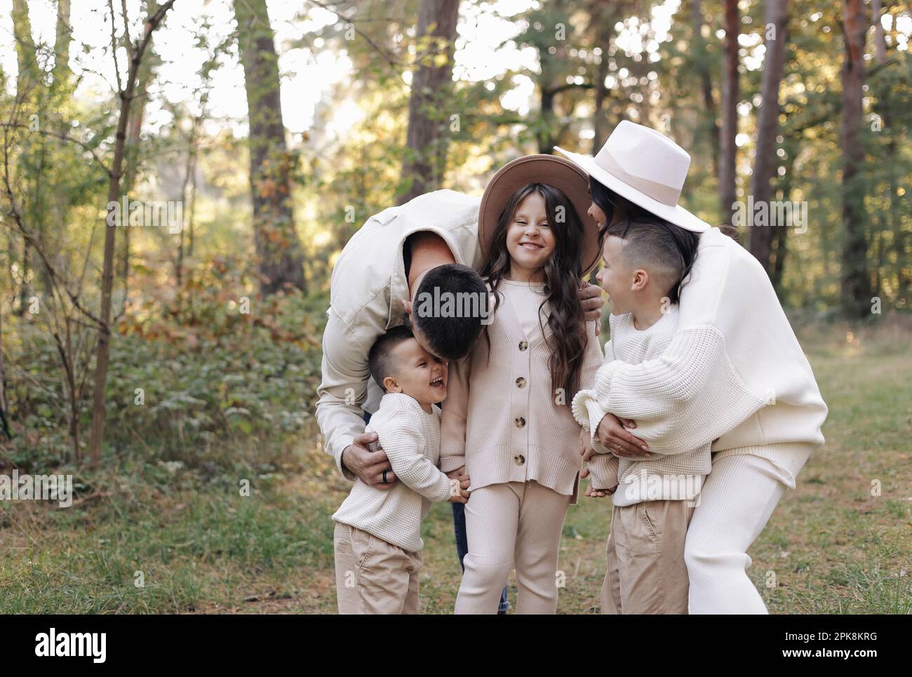 Young mother, father with daughter and sons are walking, having fun in autumn forest. Family ...