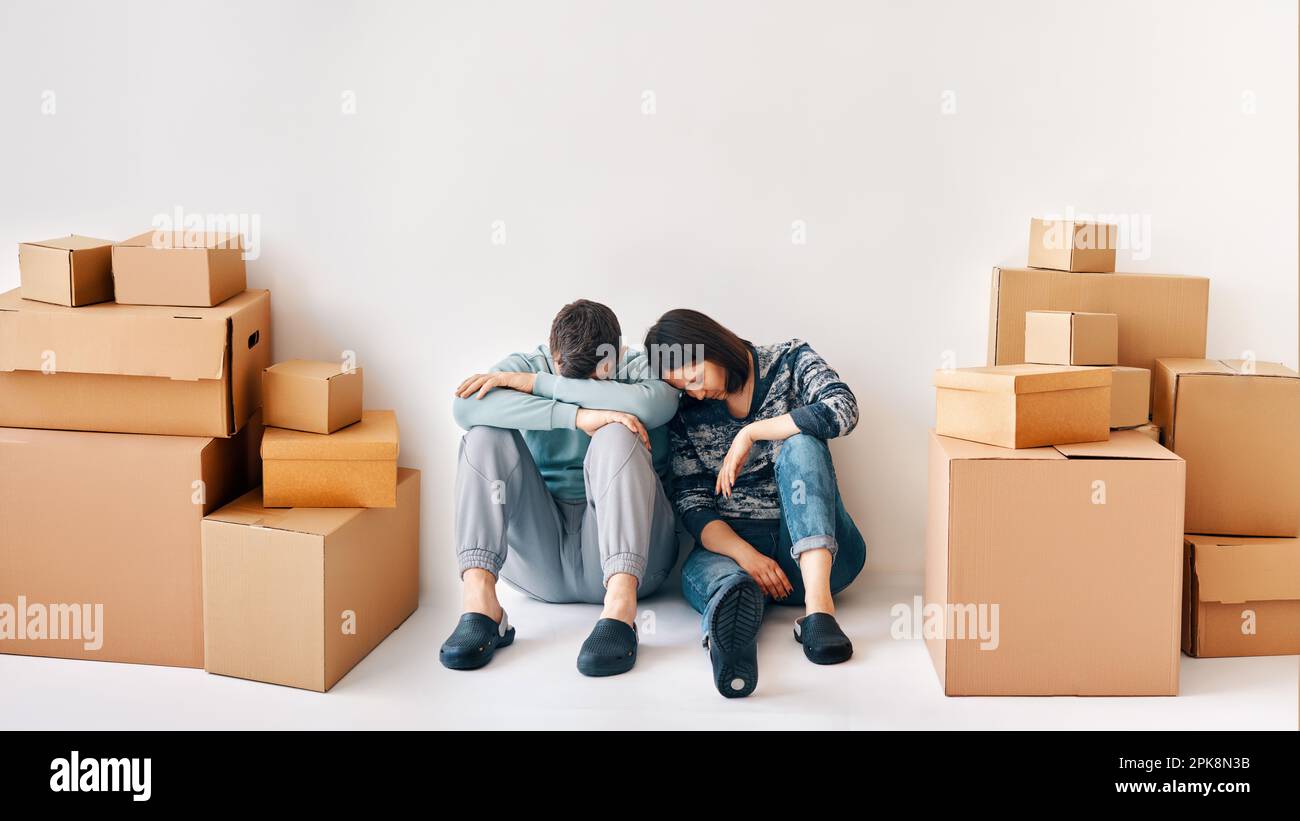 Young couple fell asleep after a moving day sitting on the floor ...