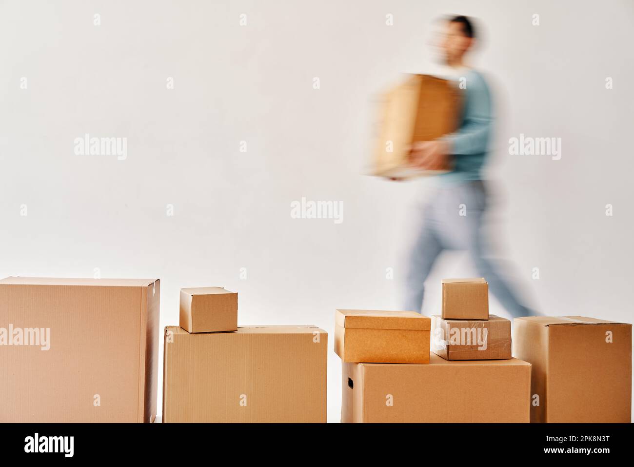 Blurred motion of young man carrying cardboard boxes moving to new ...