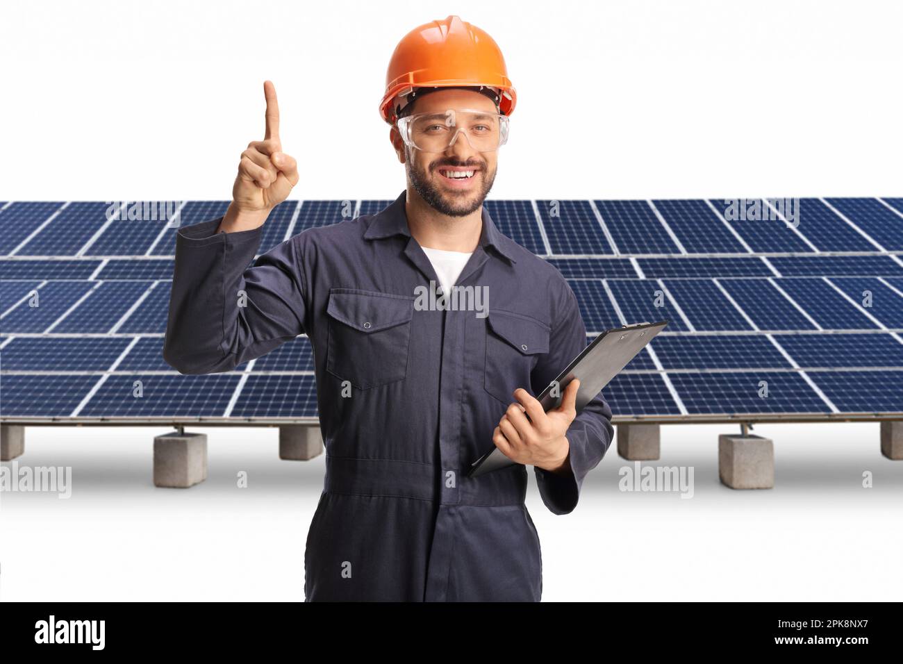 Factory worker standing in front of solar panels and pointing up ...