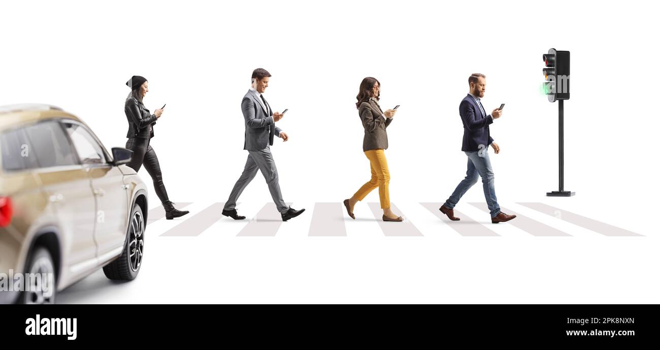 People crossing street at a pedestrian crossing and using mobile phones ...