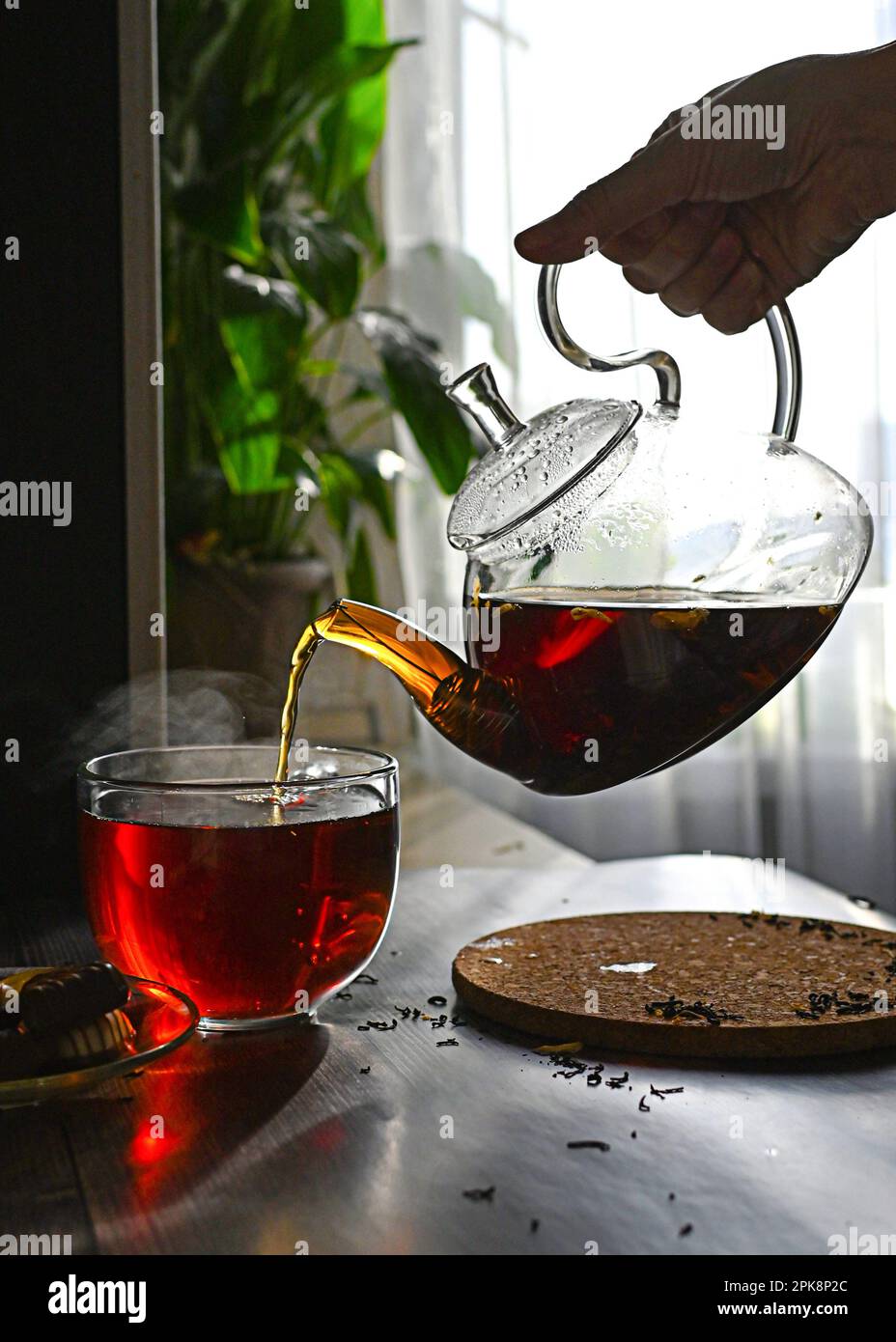A woman's hand pouring tea into a mug. Steamed tea, morning tea, home ...