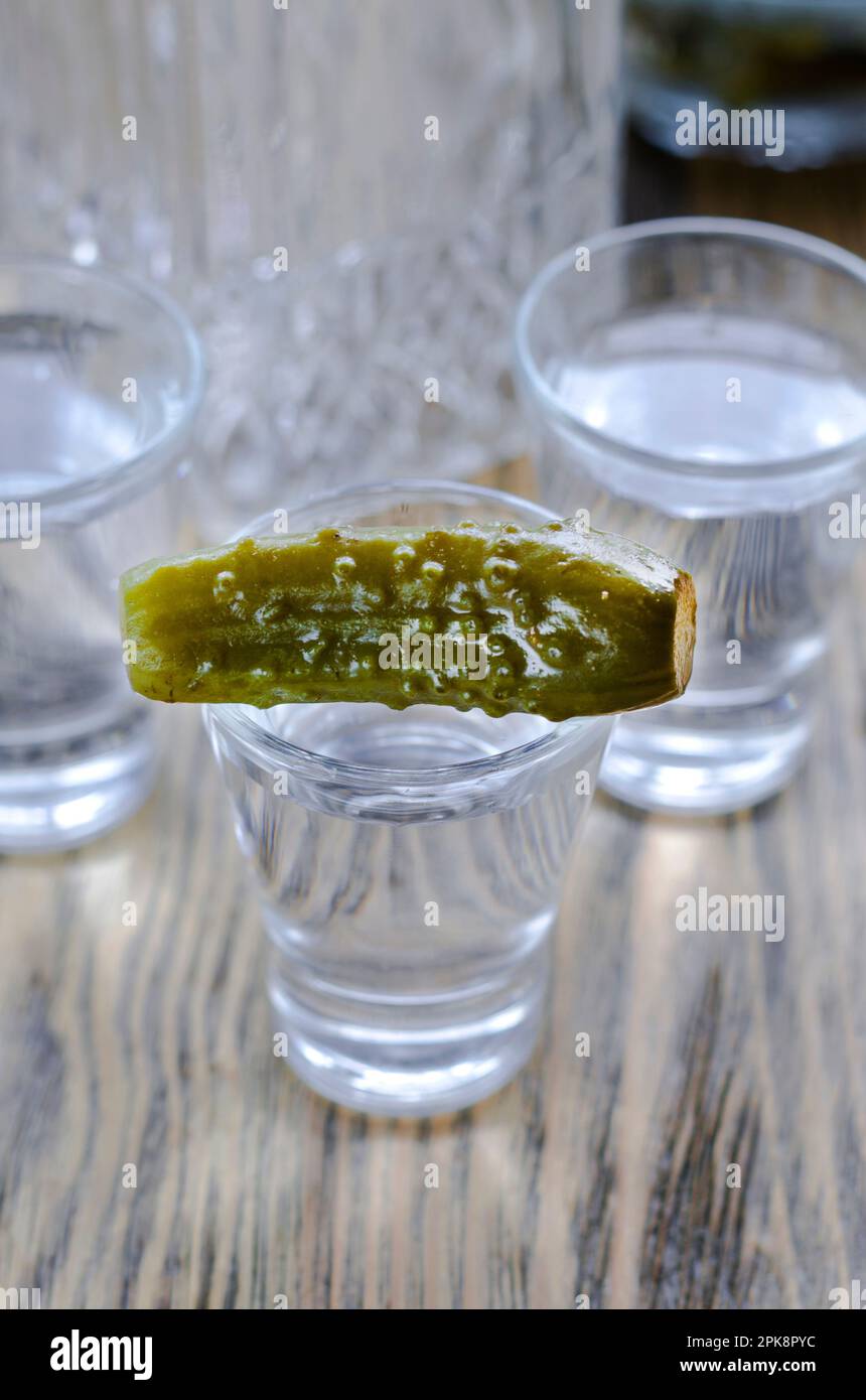 Vodka in a glass and pickled cucumber. Traditional Russian alcoholic ...