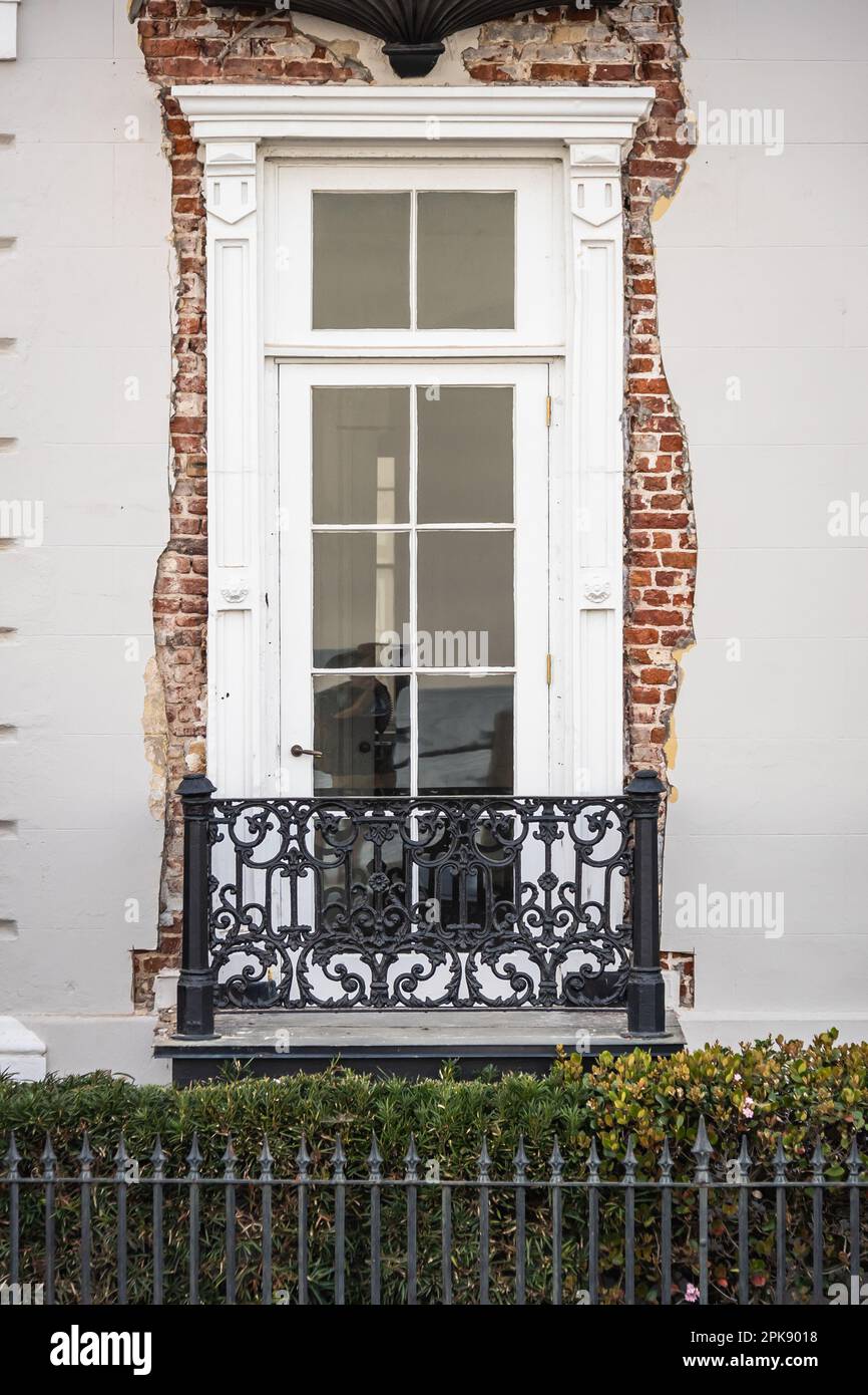 A colonial ear window with a small balcony with eroded stucco siding ...