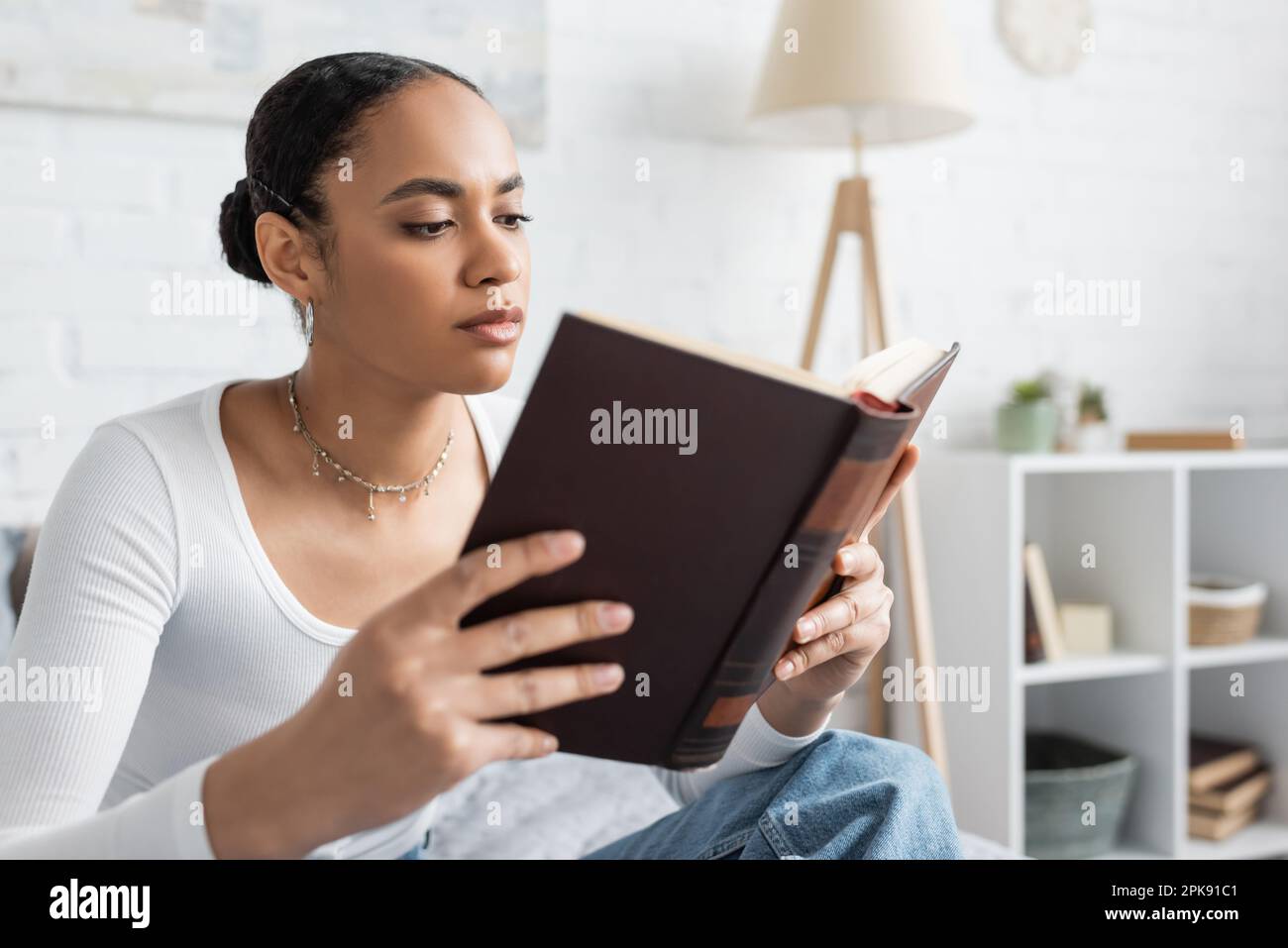 Focused african american student reading book at home,stock image Stock ...