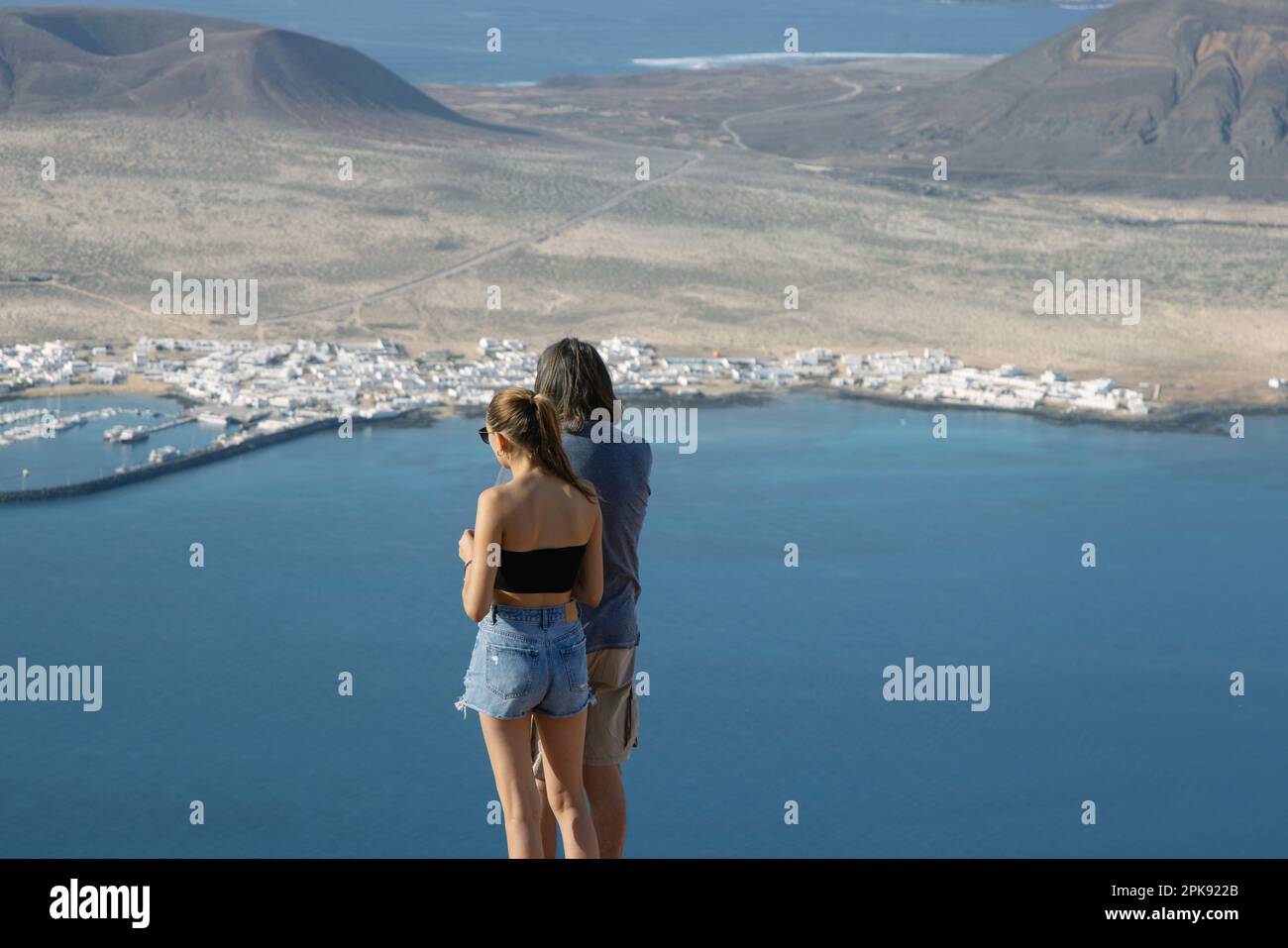 Man and girl standing at a viewpoint looking at La Graciosa island ...