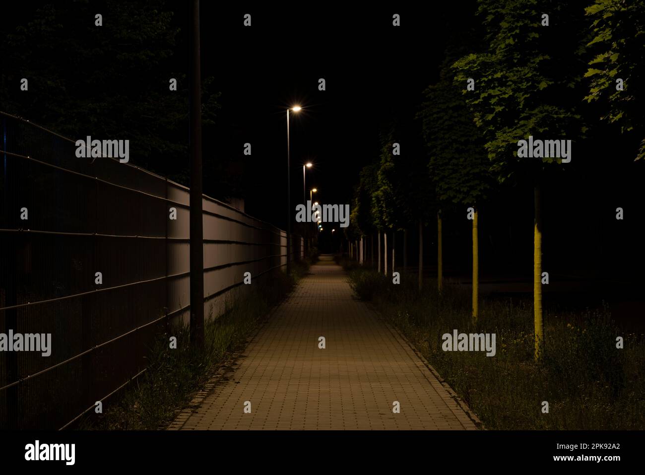 Small cycle path at night next to a road in the small town of ...