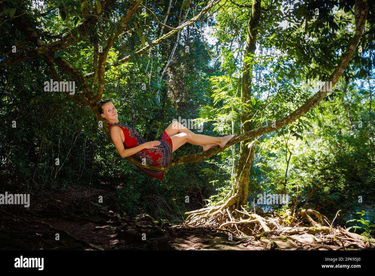 Young pretty woman in Roberto Barrios cascadas park, sitting on a tree ...