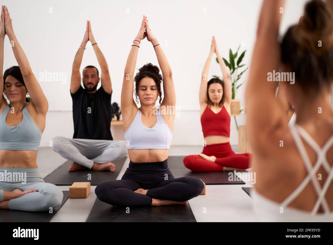 Group of people in a yoga class indoors, closing eyes and learning ...