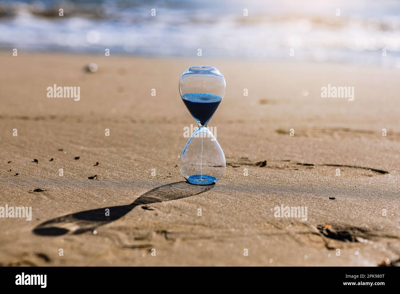 Hourglass with blue sand inside in a warm golden morning sunlight with ...