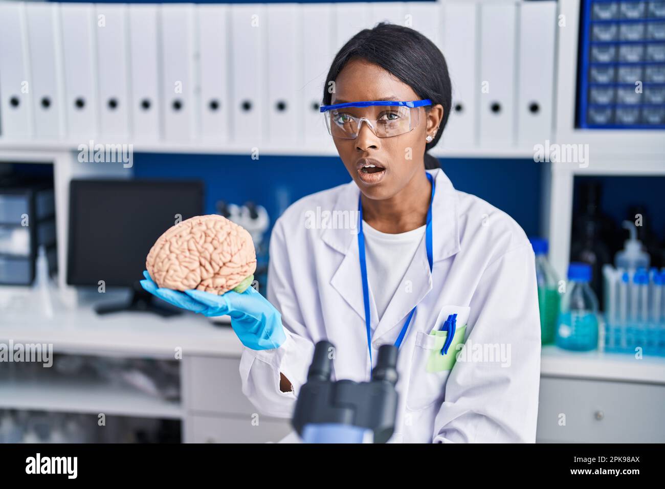 African young woman working at scientist laboratory holding brain ...