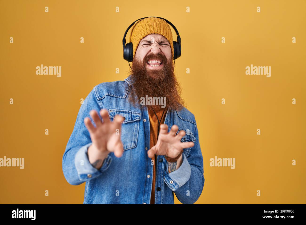 Caucasian man with long beard listening to music using headphones ...