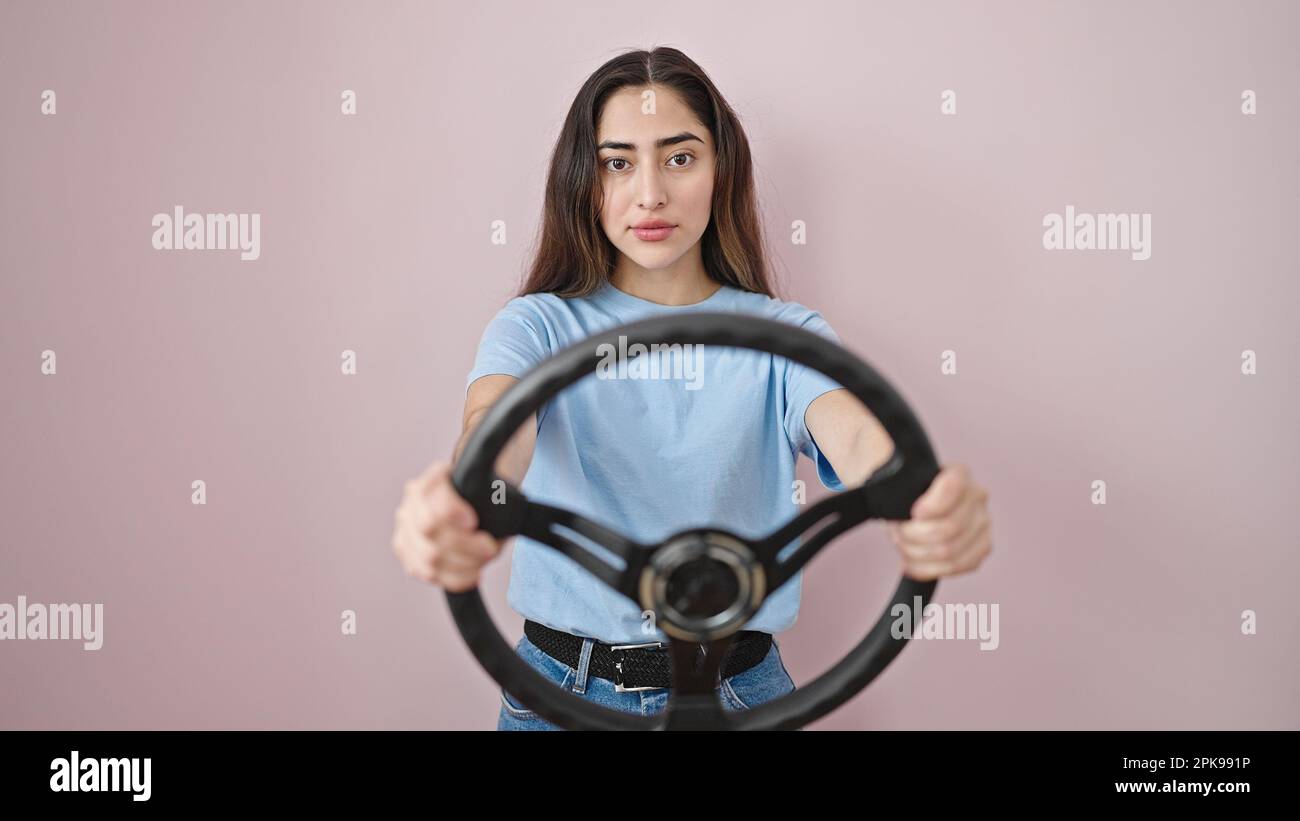 Young beautiful hispanic woman using steering wheel as a driver over ...