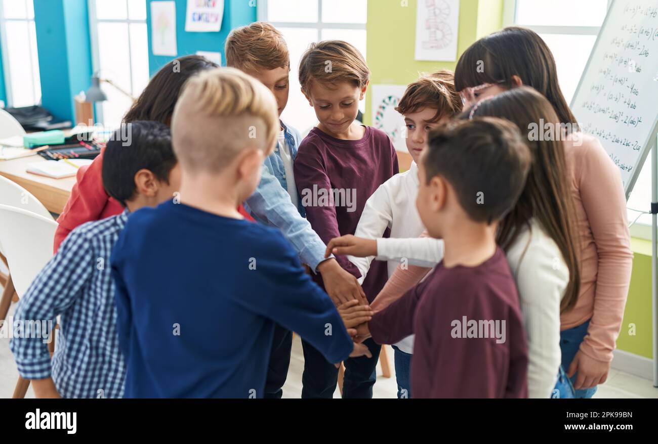Group of kids students with hands together at classroom Stock Photo - Alamy