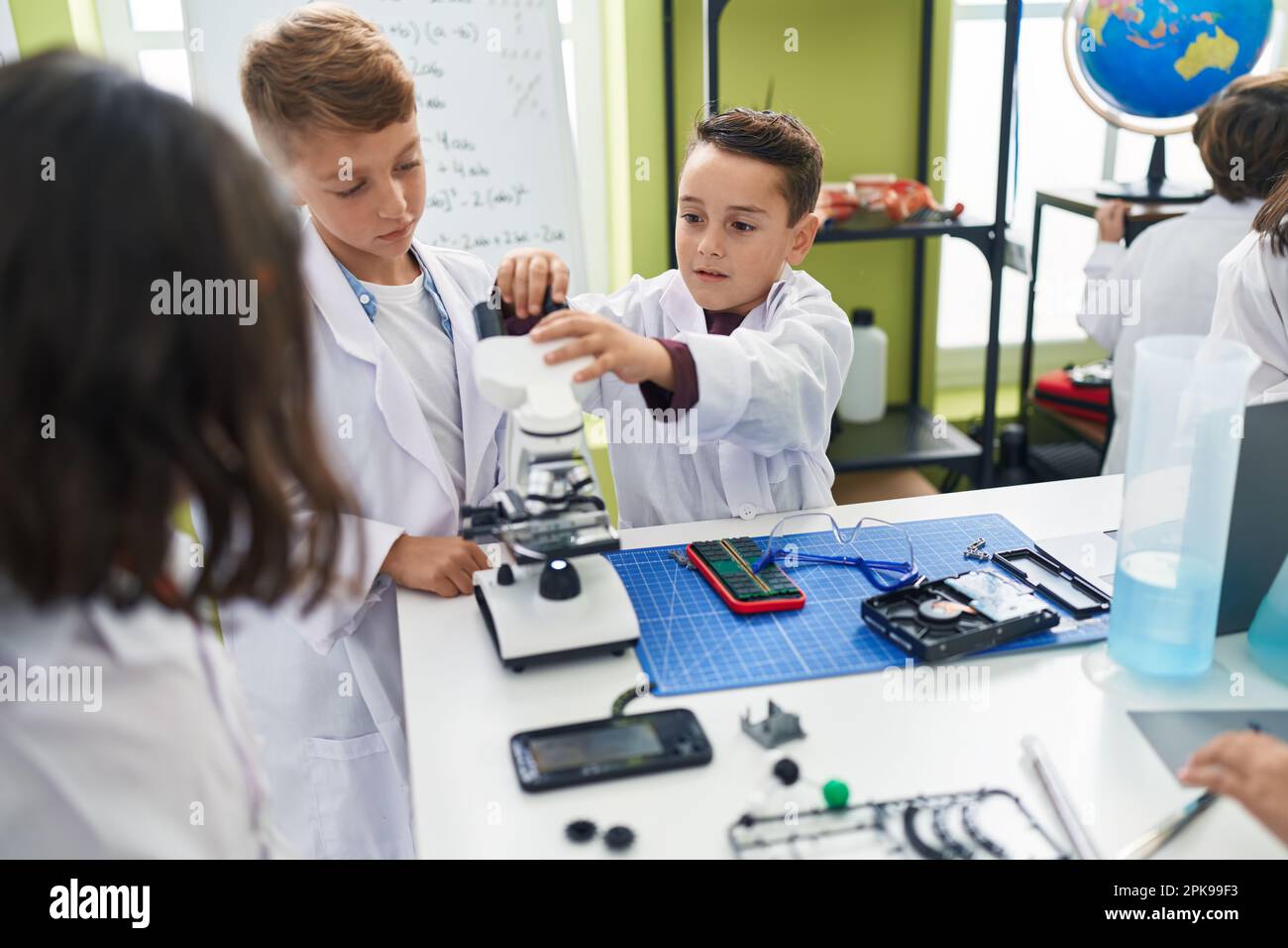 Group of kids students using microscope repairing smartphone at ...