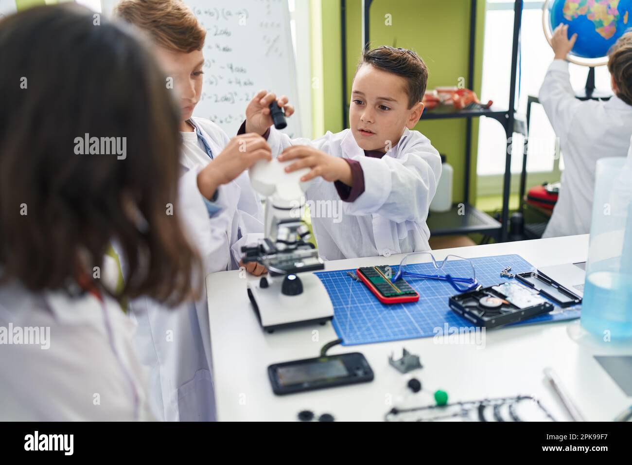 Group of kids students using microscope repairing smartphone at ...