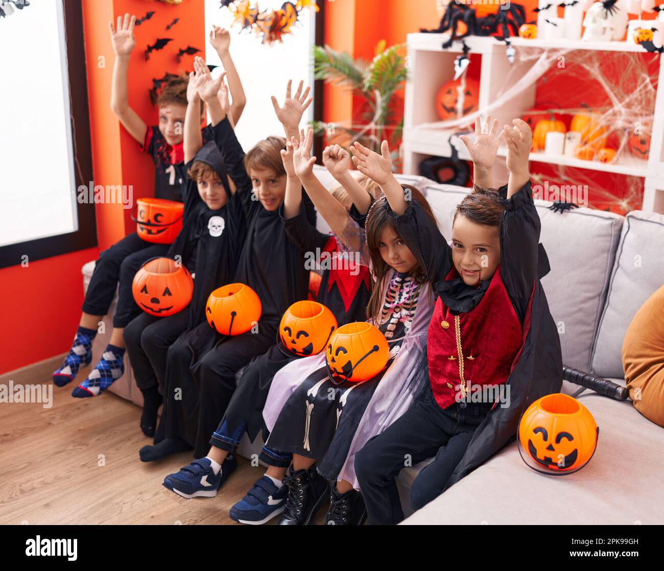 Group of kids wearing halloween costume with hands raised up at home ...