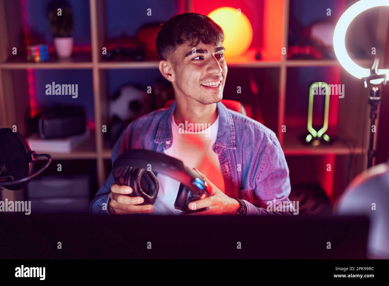 Young hispanic man streamer smiling confident holding headphones at ...