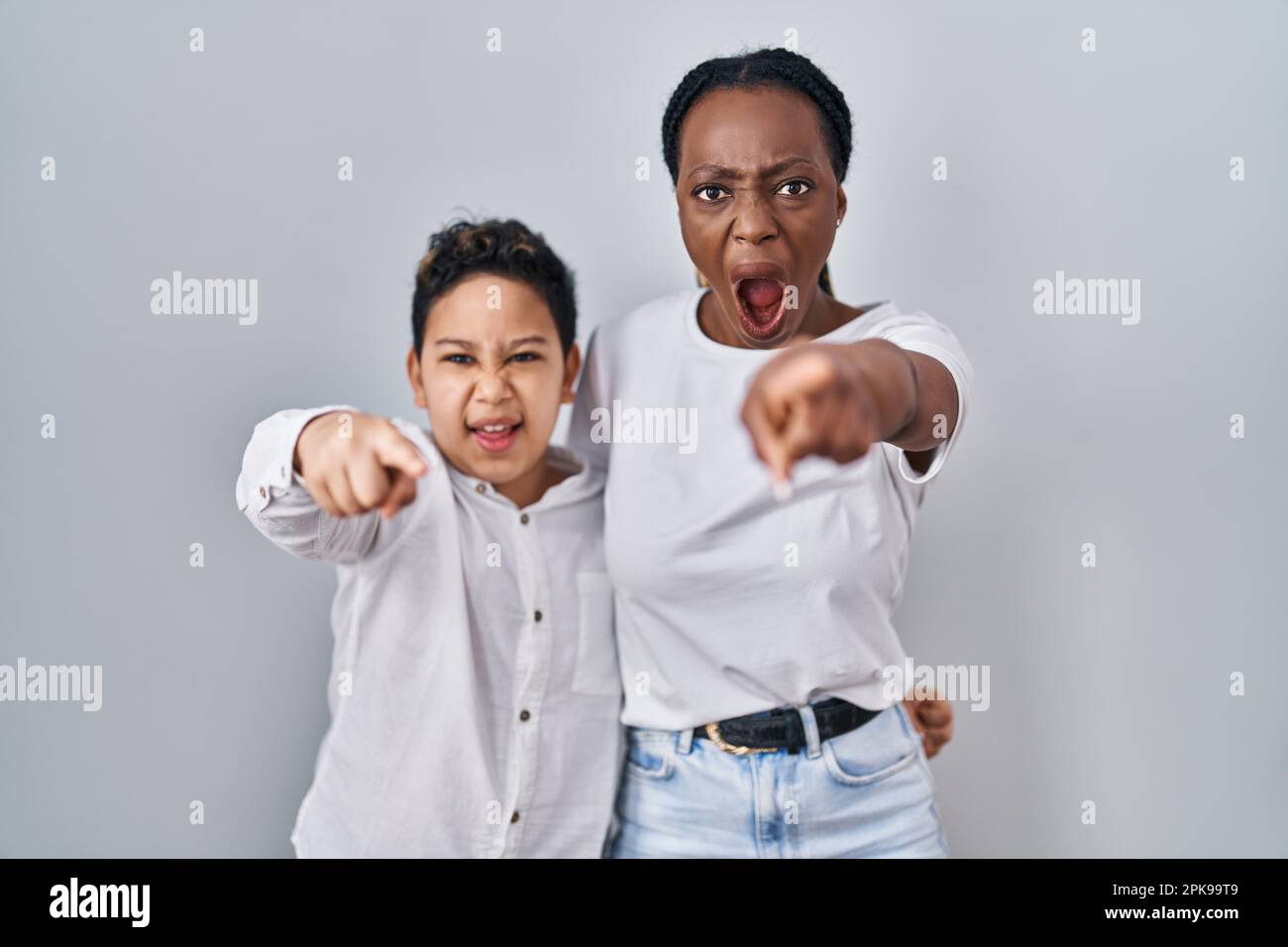 Young mother and son standing together over white background pointing ...