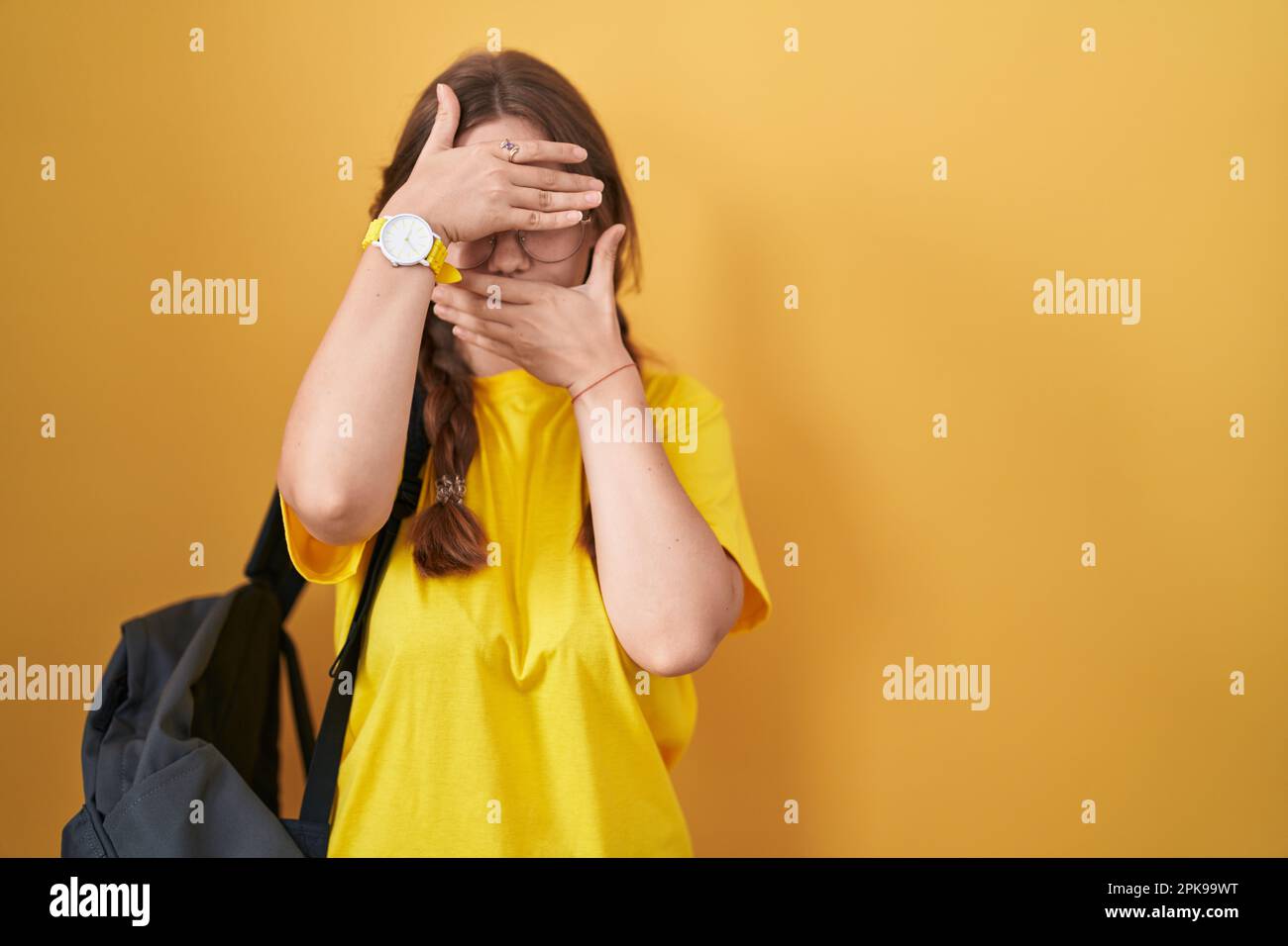 Young caucasian woman wearing student backpack over yellow background ...