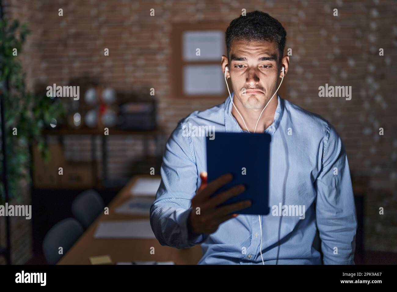 Handsome hispanic man working at the office at night depressed and ...