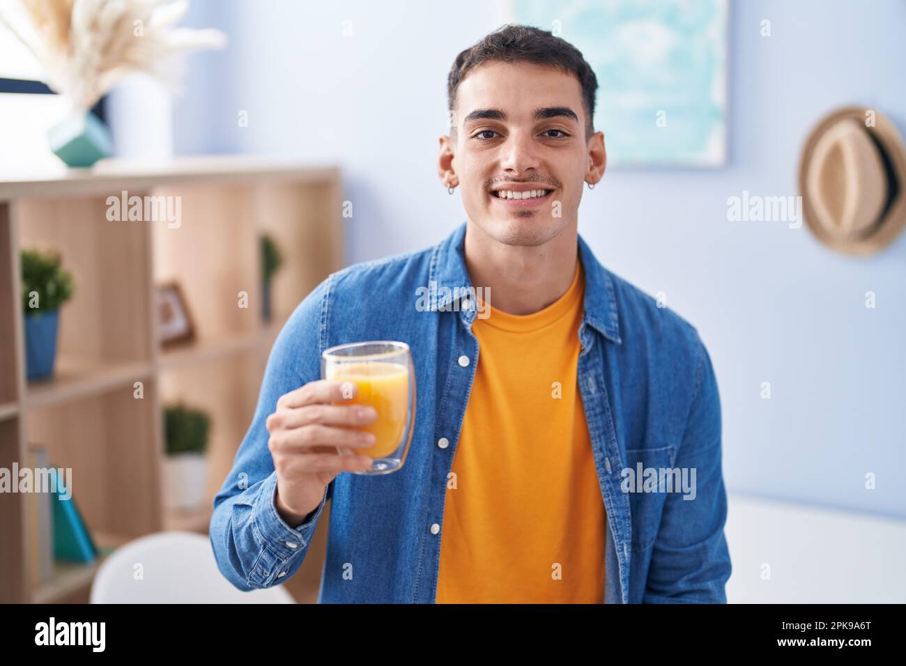 Handsome hispanic man drinking glass of orange juice looking positive ...