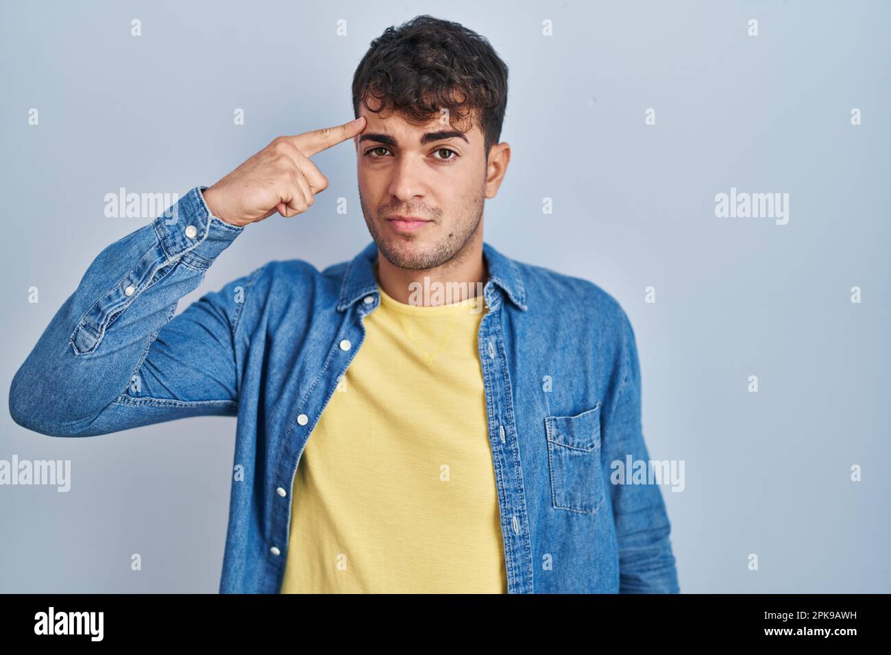Young hispanic man standing over blue background pointing unhappy to ...