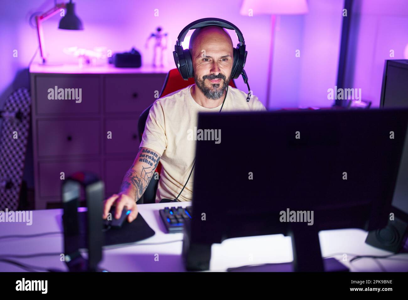 Young bald man streamer playing video game using computer at gaming ...