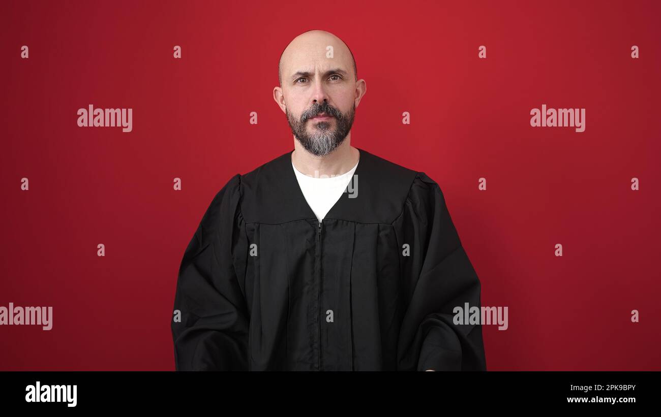 Young bald man wearing costume standing over isolated red background ...