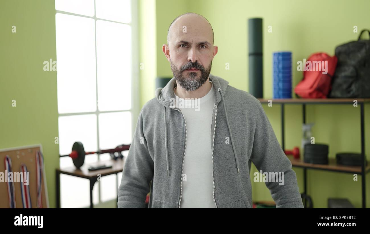 Young bald man standing with relaxed expression at sport center Stock ...