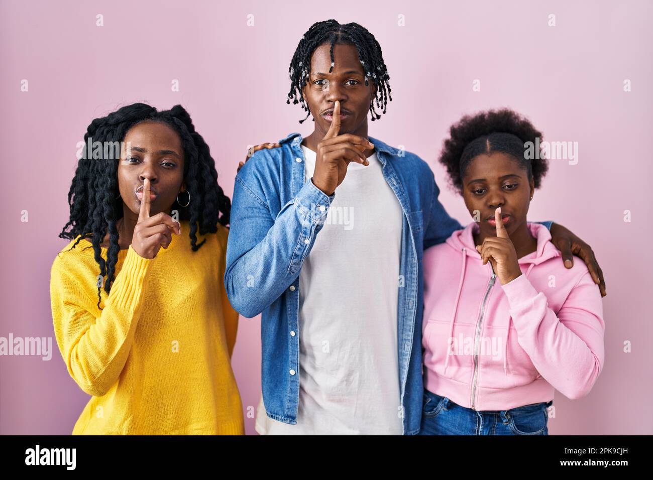 Group of three young black people standing together over pink ...