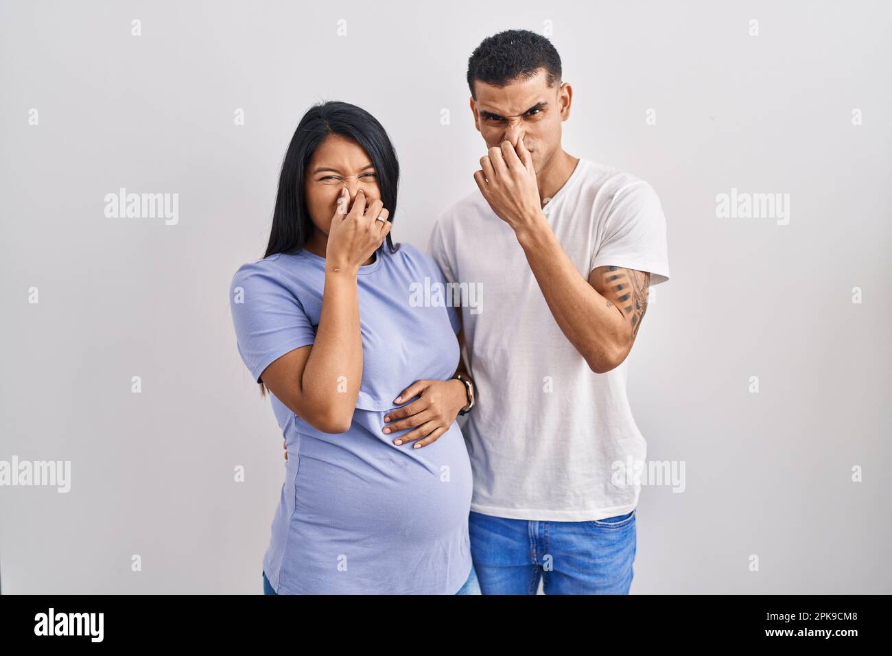Young hispanic couple expecting a baby standing over background ...
