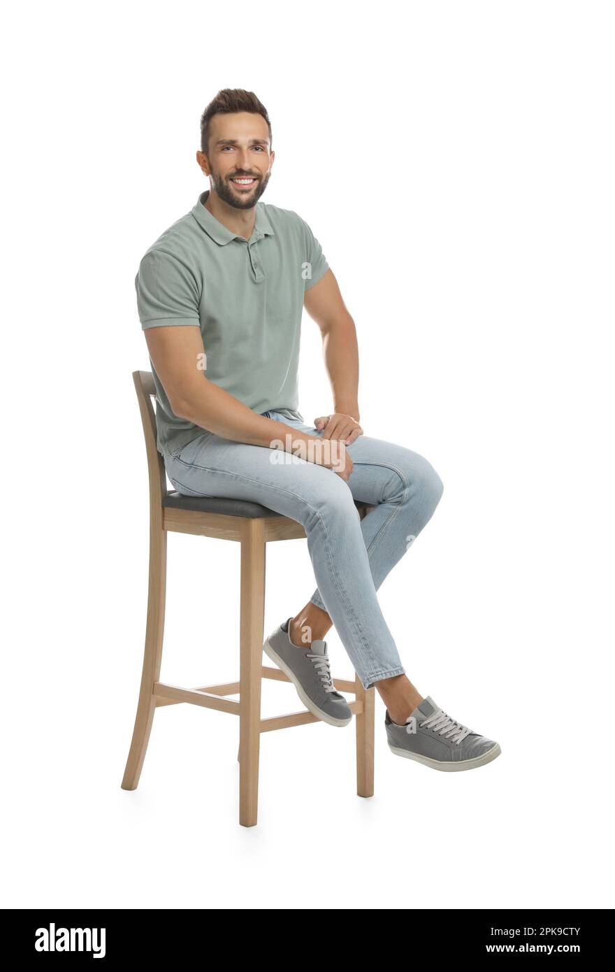 Handsome man sitting on stool against white background Stock Photo - Alamy