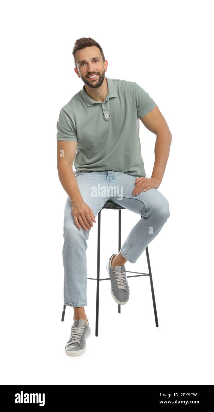 Handsome man sitting on stool against white background Stock Photo - Alamy