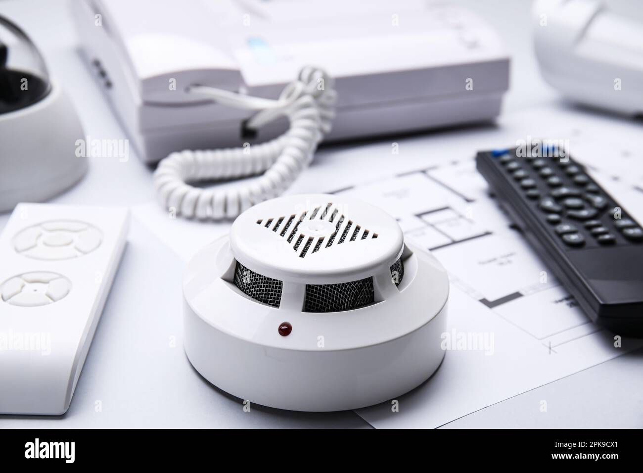 Smoke detector, remote controls and building plan on white background ...