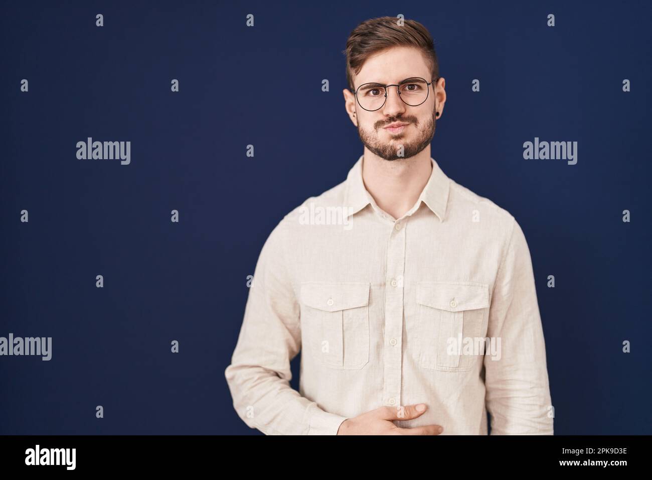 Hispanic man with beard standing over blue background puffing cheeks ...