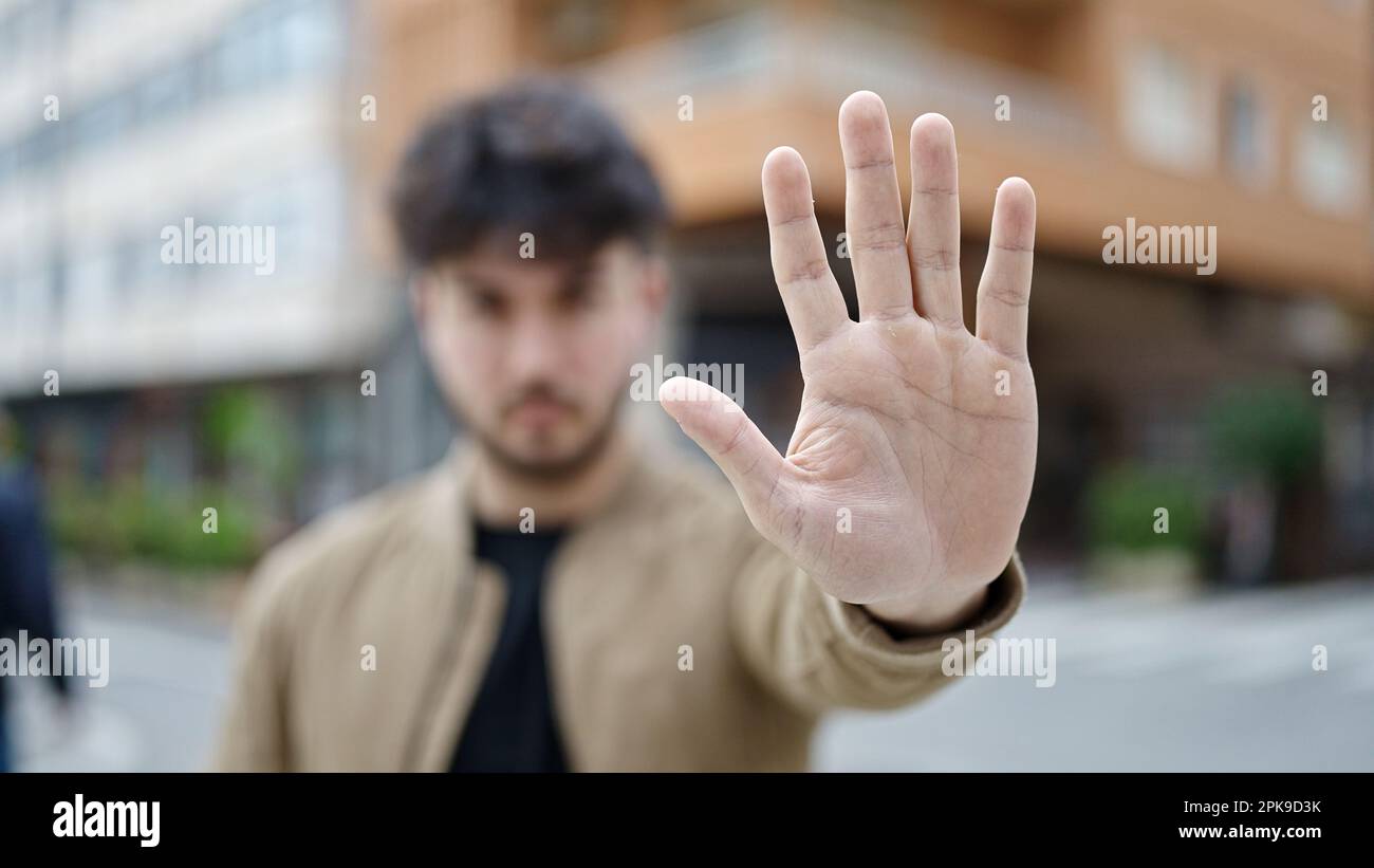 Young hispanic man doing stop gesture with hand at street Stock Photo ...
