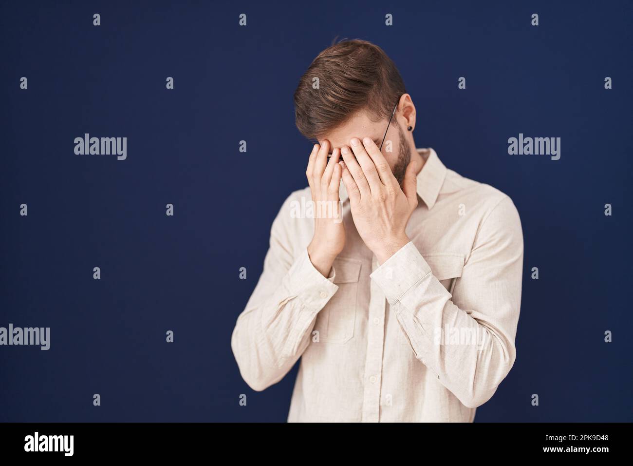 Hispanic man with beard standing over blue background with sad ...