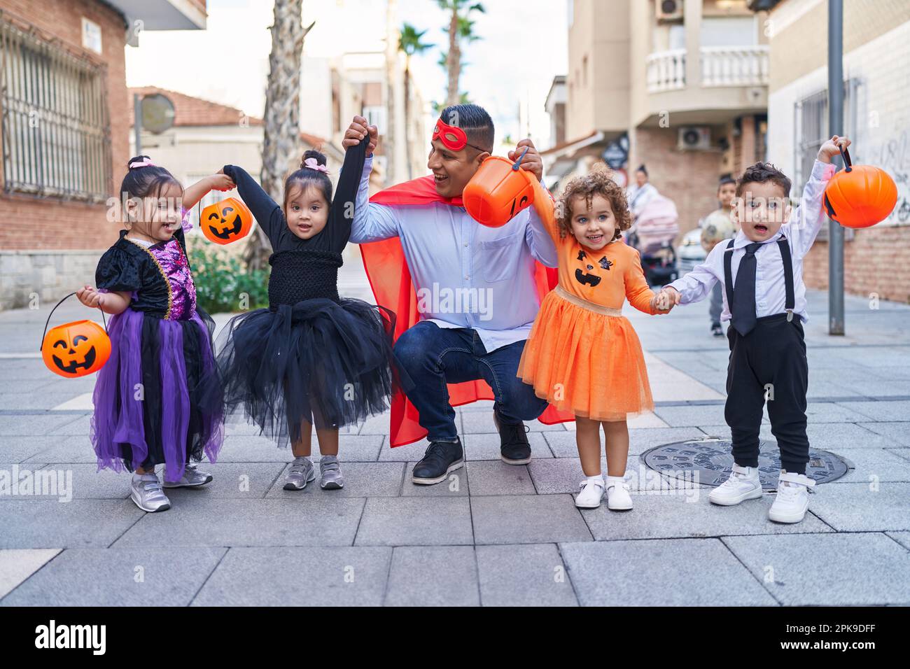 Hispanic man and group of kids wearing halloween costume smiling at ...
