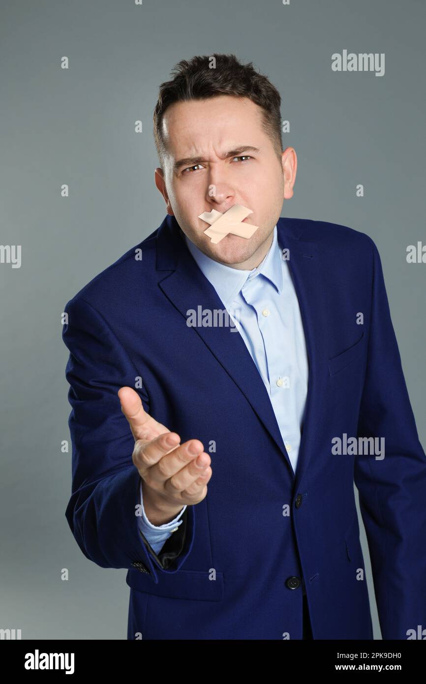 Man with taped mouth on grey background. Speech censorship Stock Photo ...