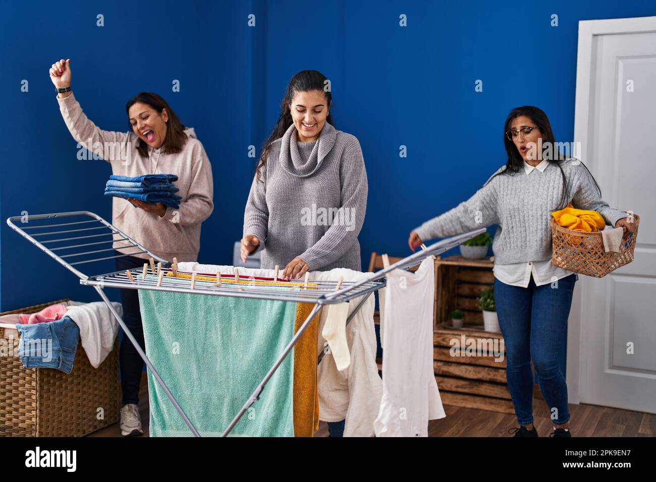 Three woman hanging clothes on clothesline and dancing at laundry room ...