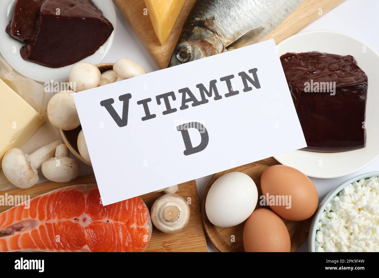 Paper with phrase VITAMIN D and fresh products on white background ...
