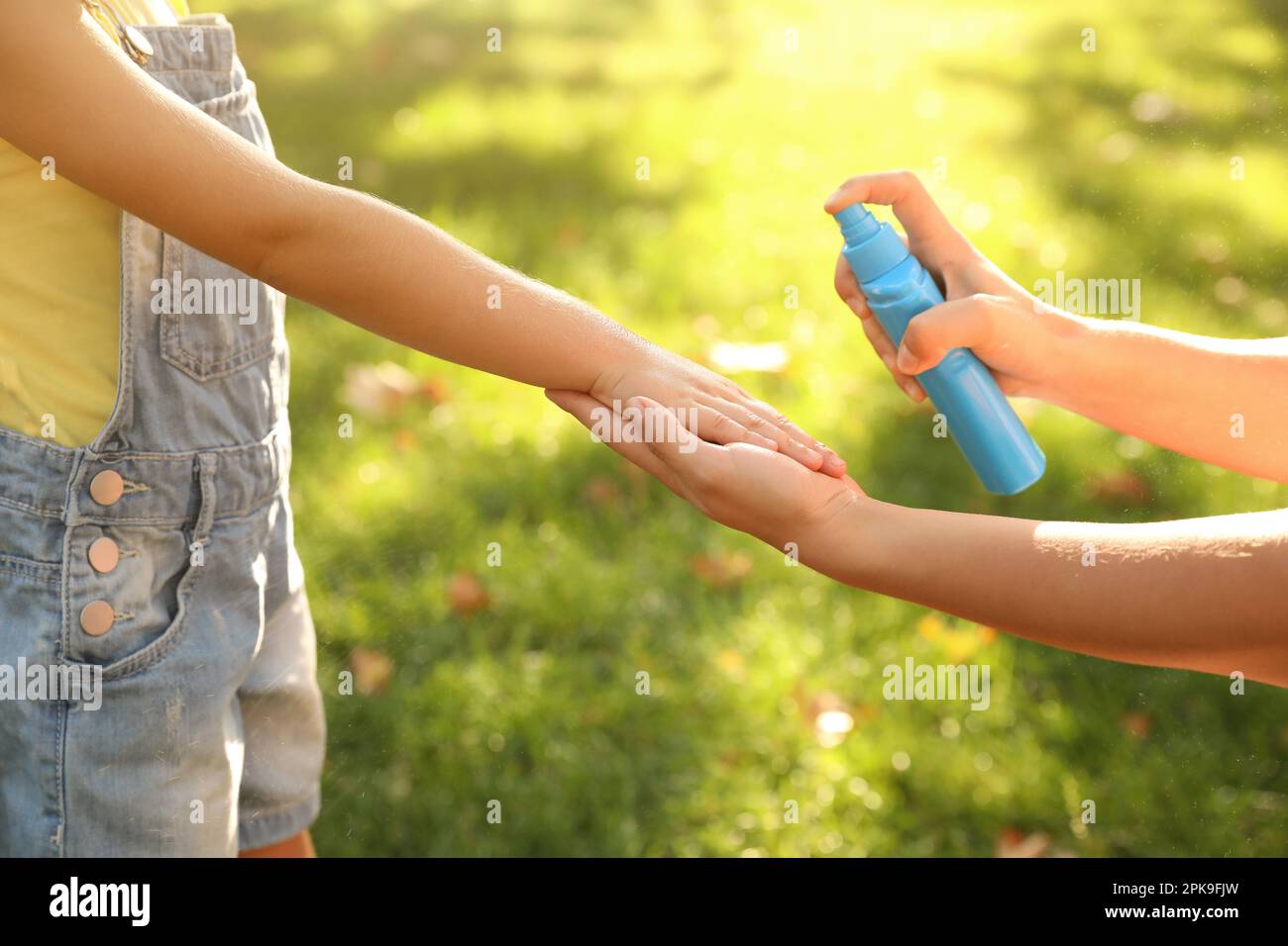 Mother applying insect repellent onto girl's hand in park, closeup ...