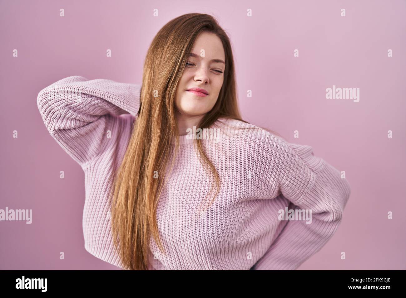 Young caucasian woman standing over pink background suffering of neck ...
