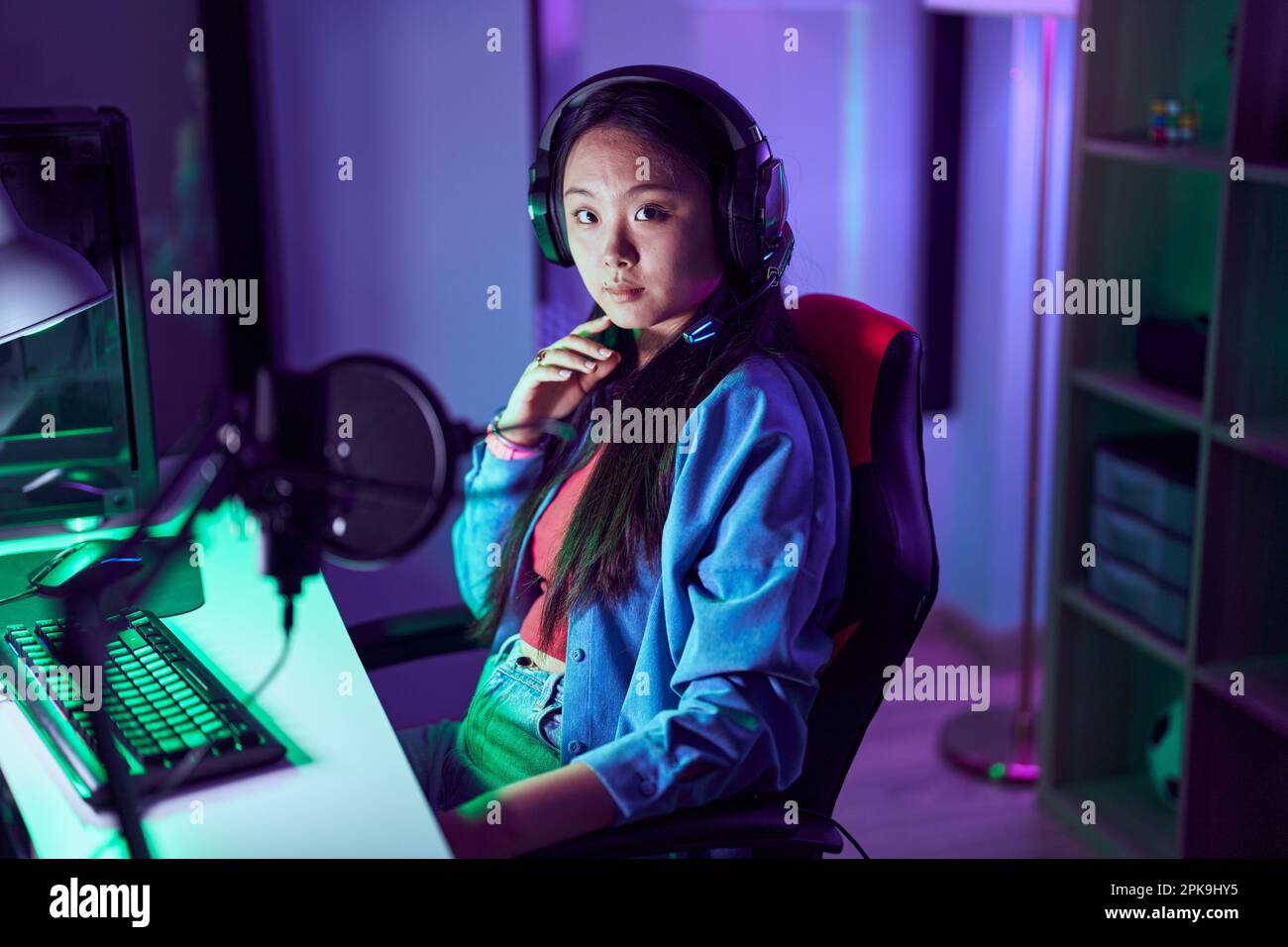 Young chinese woman streamer playing video game using computer at ...